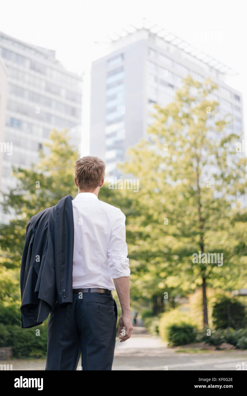 Rear view of businessman looking at office buildings Stock Photo - Alamy
