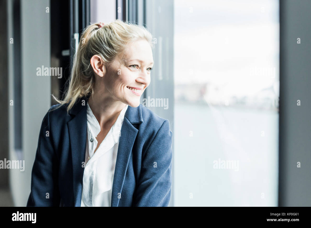 Smiling businesswoman looking out of window Stock Photo - Alamy