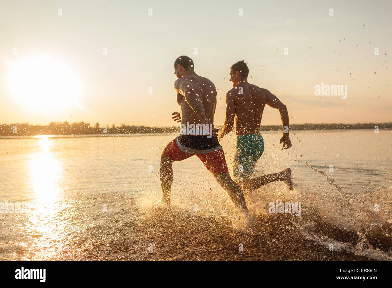 Two friends running in water Stock Photo - Alamy