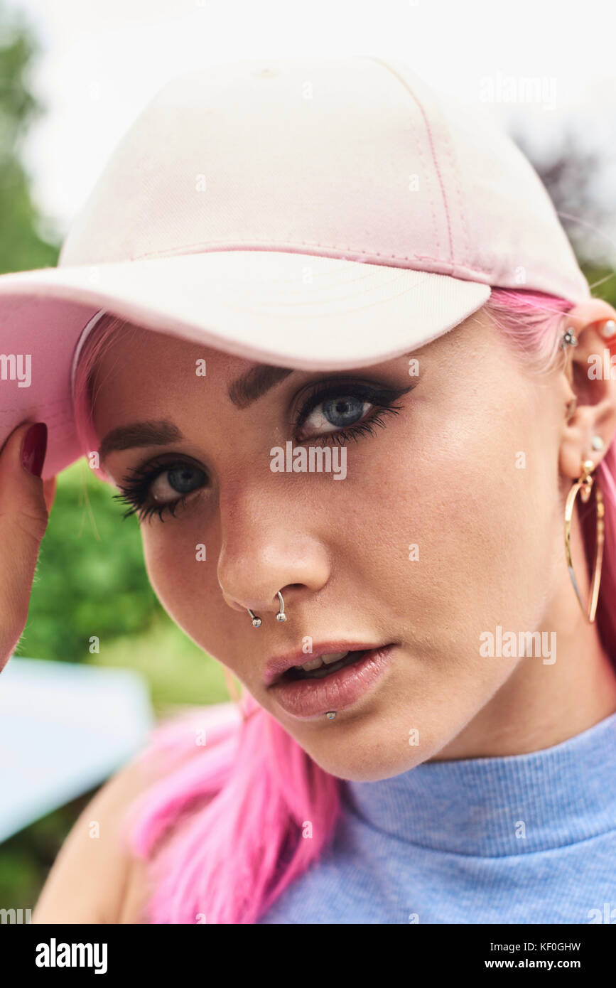 Portrait of young woman with pink hair and piercings wearing cap Stock ...