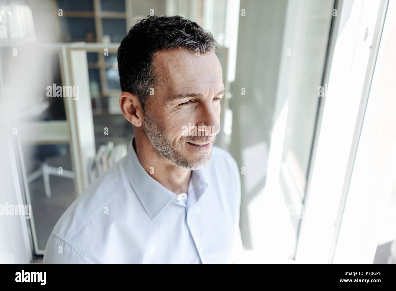 Smiling businessman looking out of window Stock Photo - Alamy