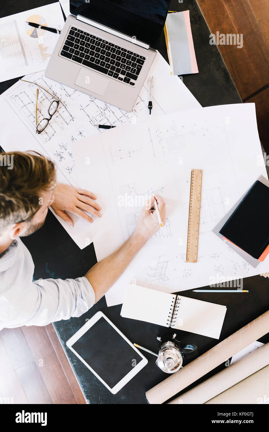 Man working on construction plan at desk, top view Stock Photo - Alamy