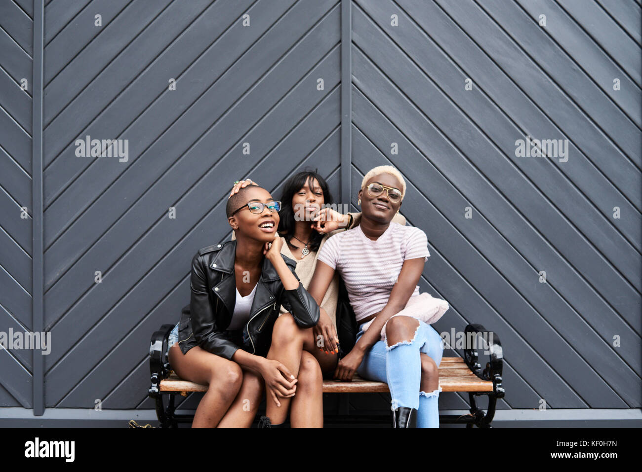 Three friends sitting together on a bench Stock Photo - Alamy