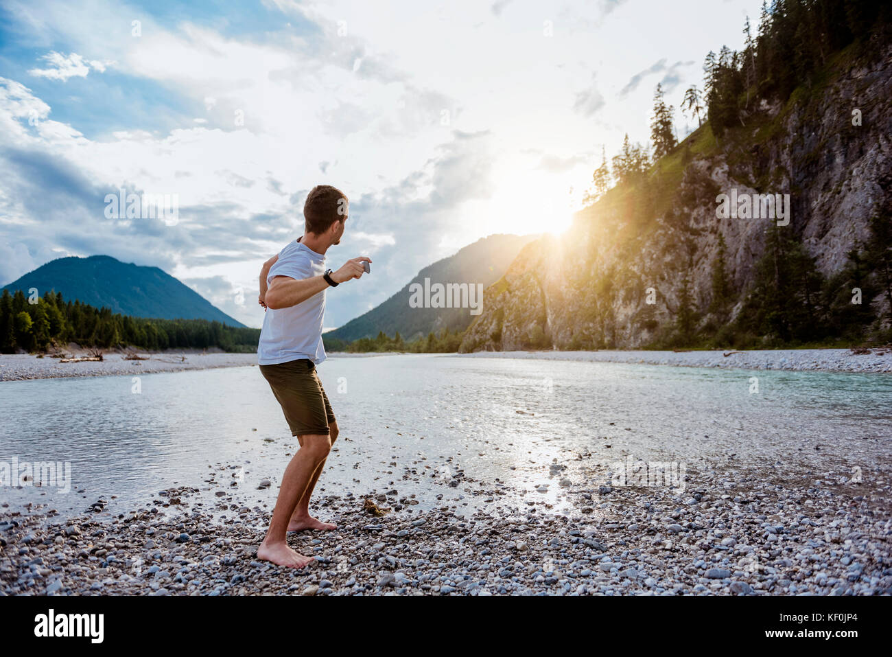 Germany, Bavaria, man standing at riverside throwing stone Stock Photo ...