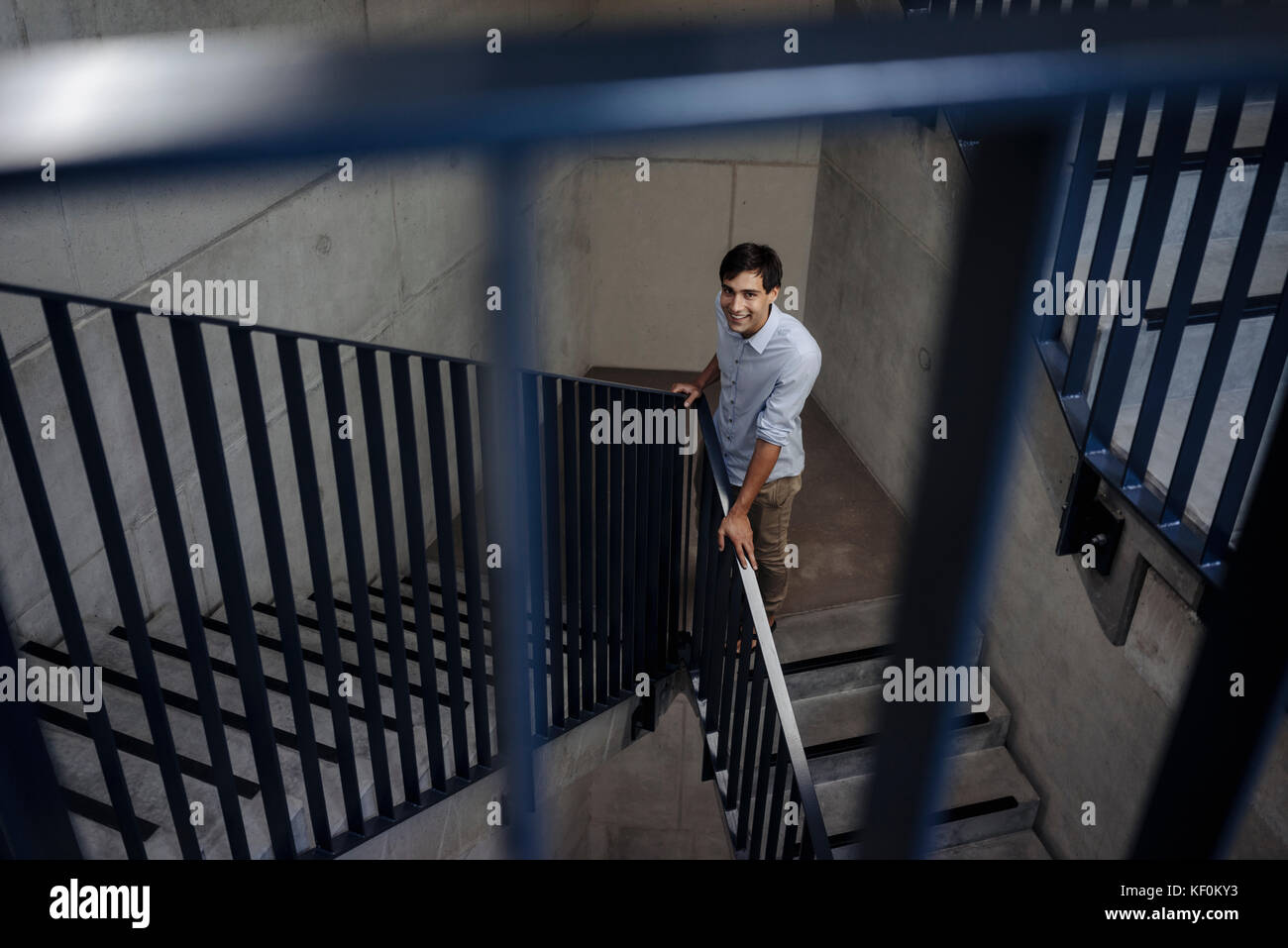 Smiling young man standing in staircase Stock Photo - Alamy