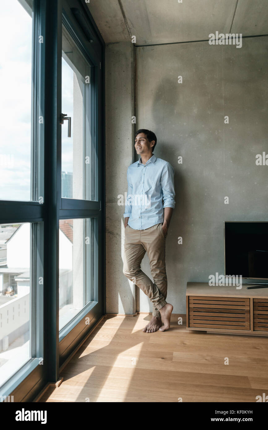 Smiling young man looking out of window Stock Photo - Alamy