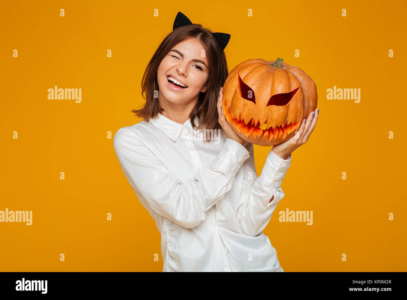 Cute teenage schoolgirl in uniform holding halloween pumpkin and ...