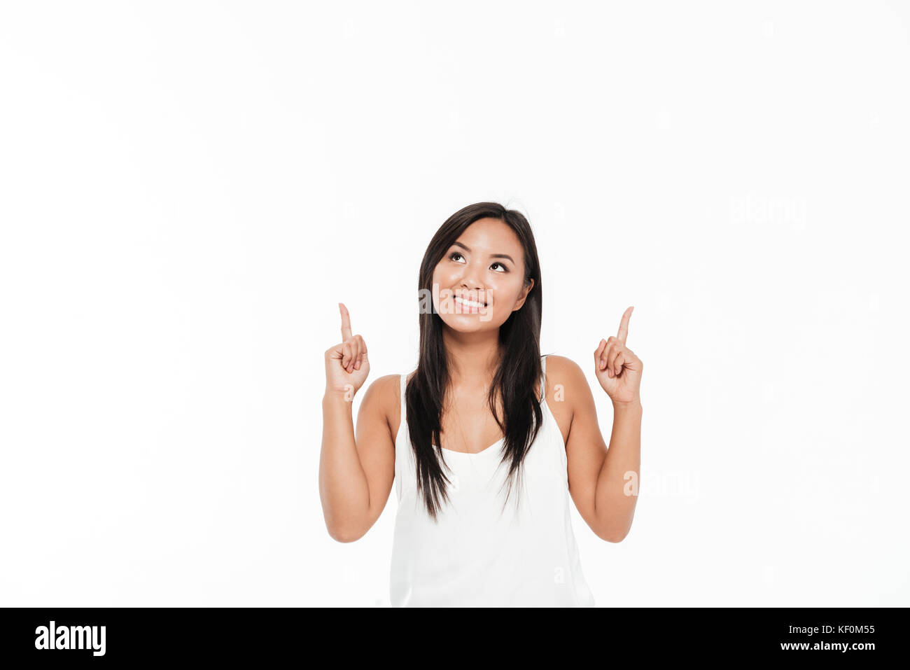 Portrait of a happy smiling asian woman pointing two fingers up at copy ...