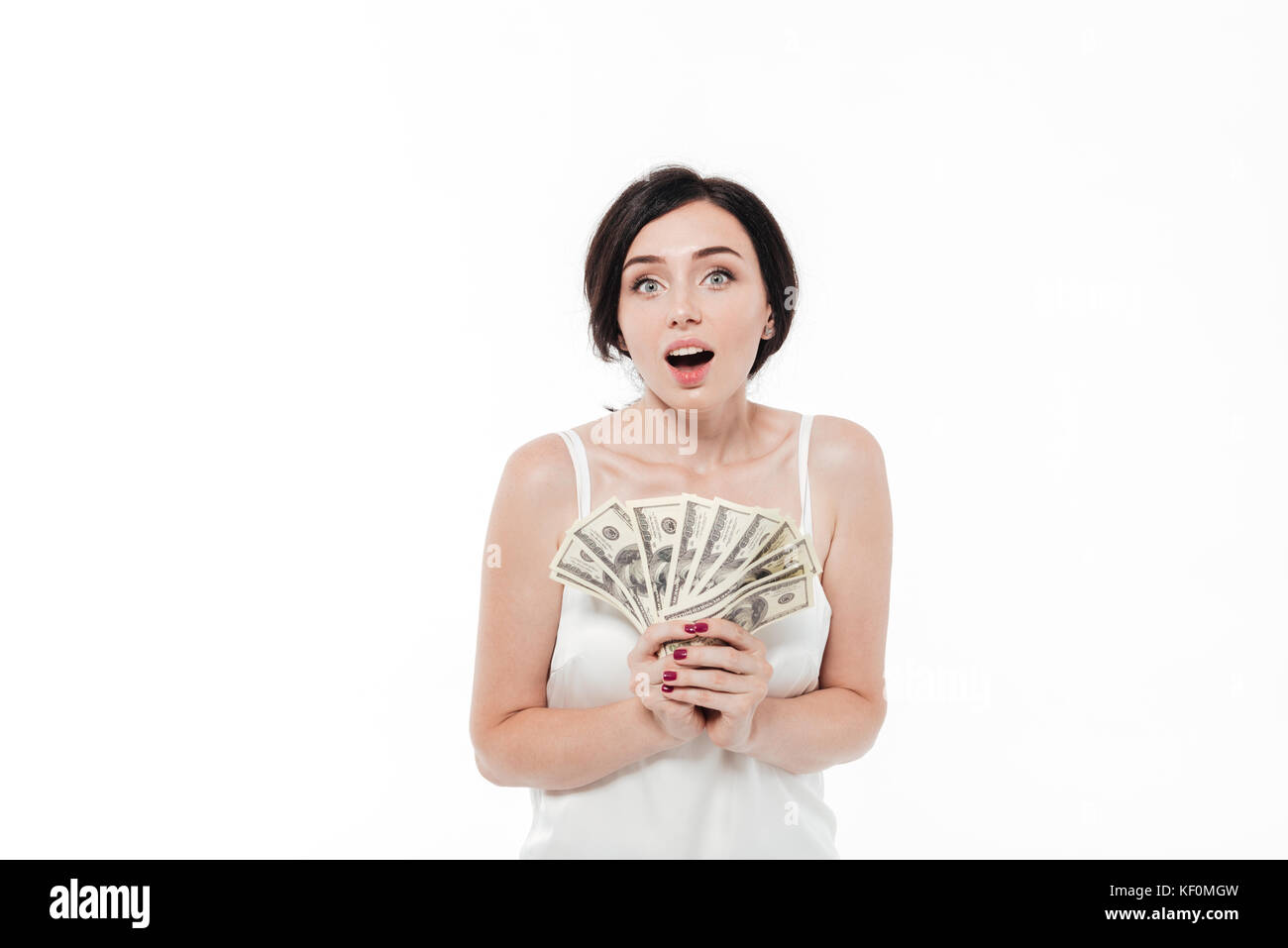 Portrait of a shocked pretty woman holding bunch of money banknotes and ...