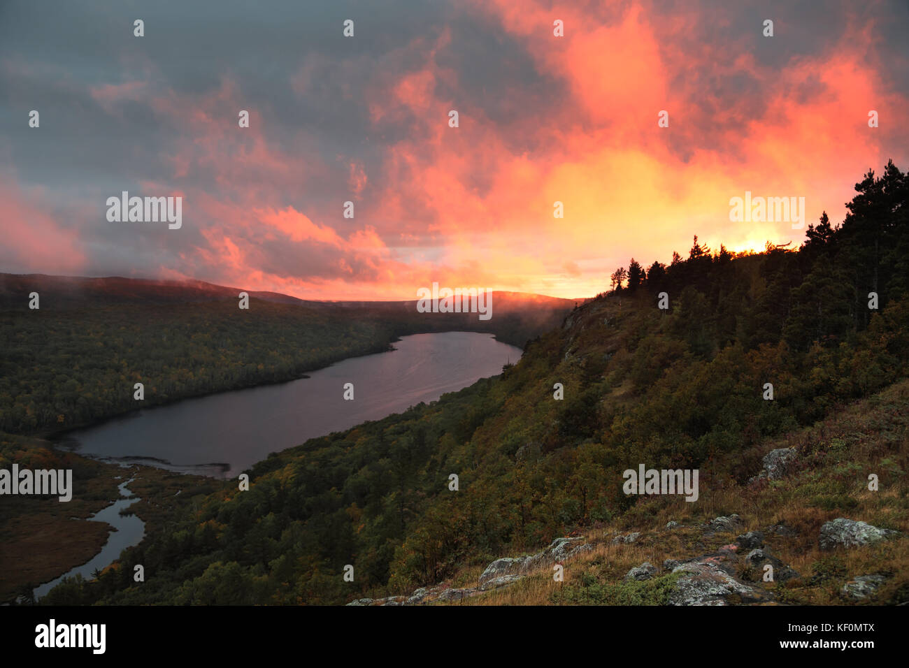 A setting sun back lights rising fog with vivid colors over Lake of the ...