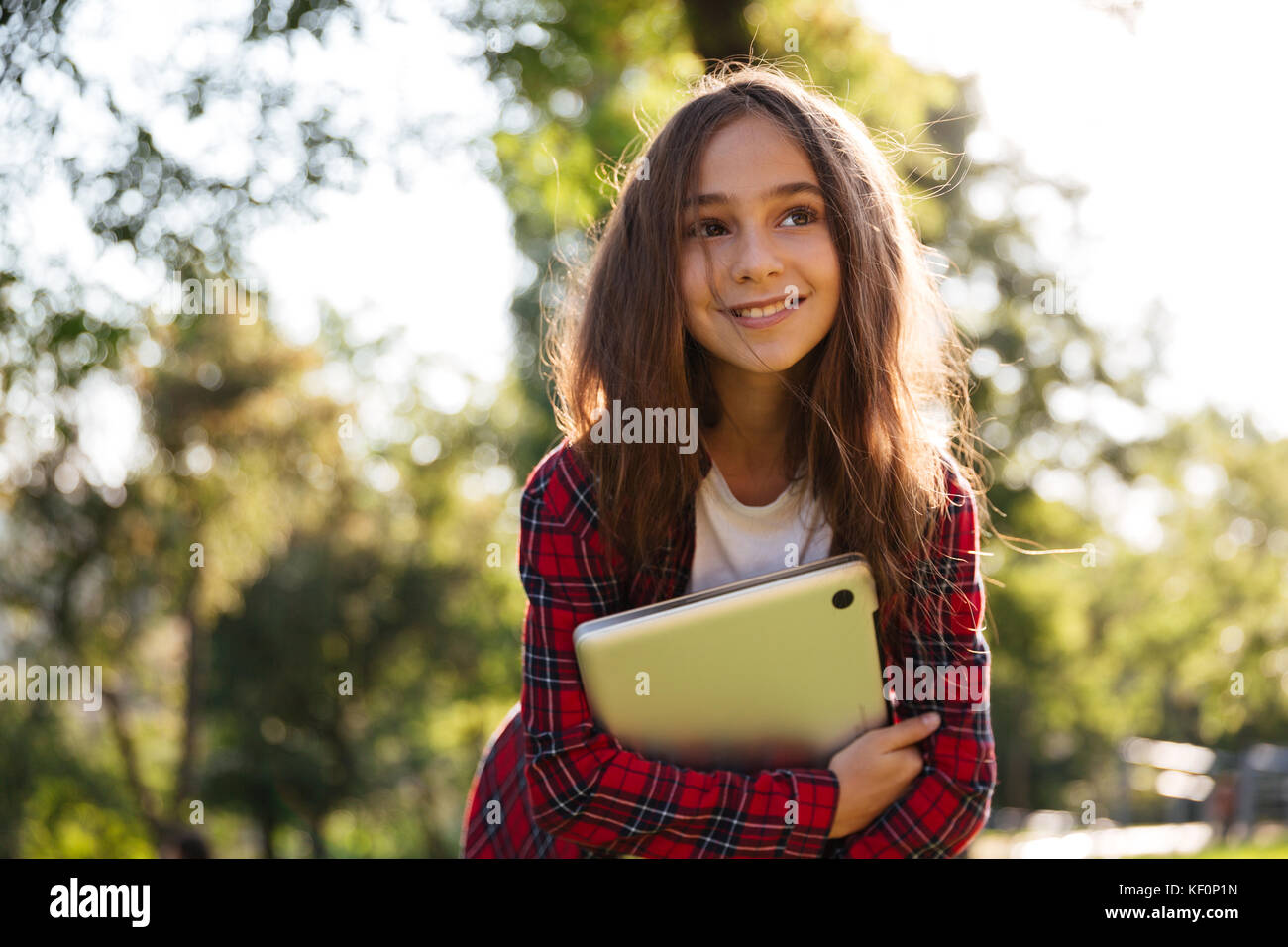 Smiling young brunette woman hugging her laptop computer and looking ...
