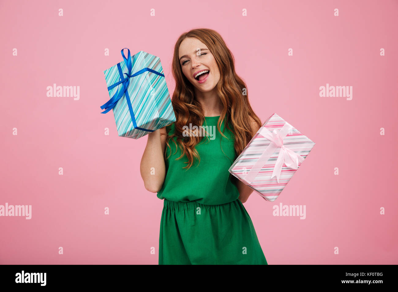 Portrait of a happy delighted woman in dress holding present boxes and ...