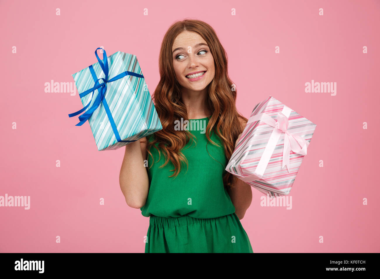 Portrait of a happy pretty woman in dress holding and showing present ...