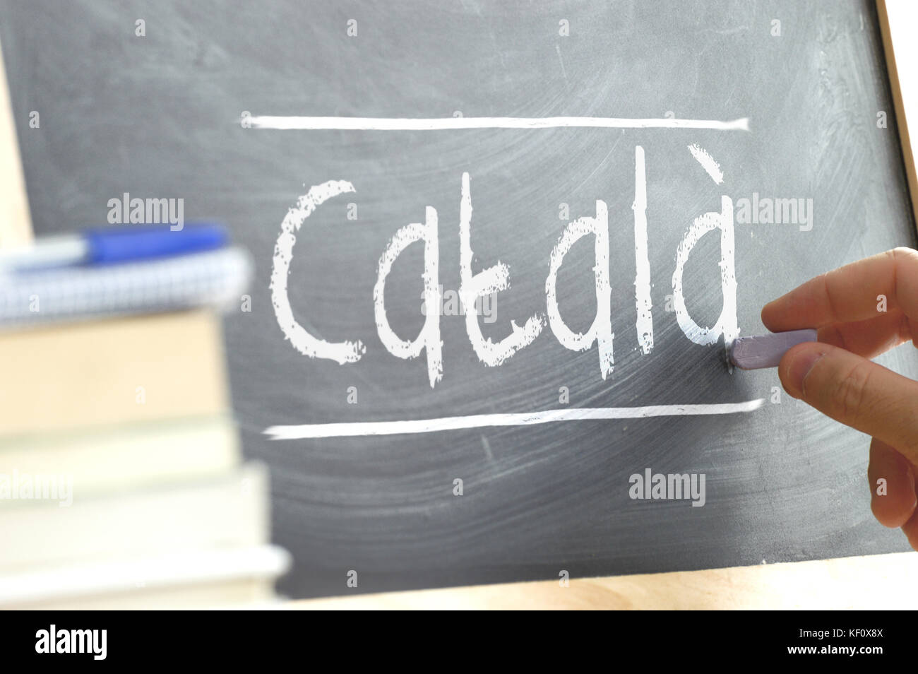 Hand writing on a blackboard in a language class with the word CATALAN ...