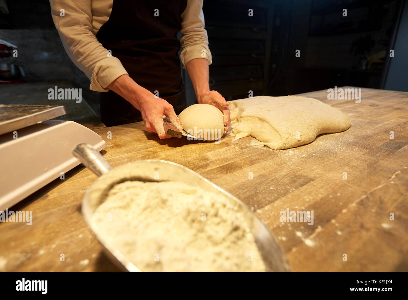baker portioning dough with bench cutter at bakery Stock Photo - Alamy