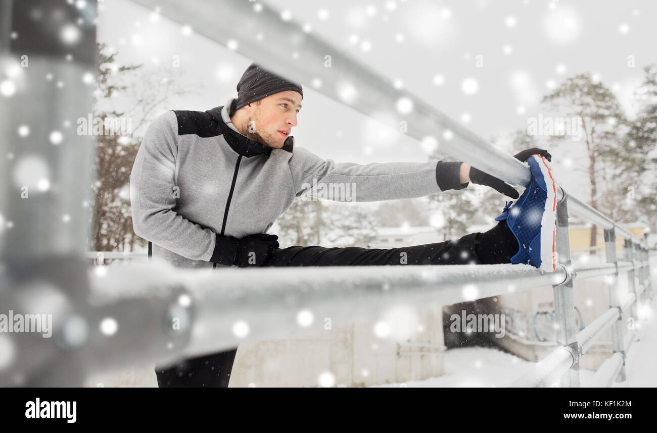 sports man stretching leg at fence in winter Stock Photo - Alamy
