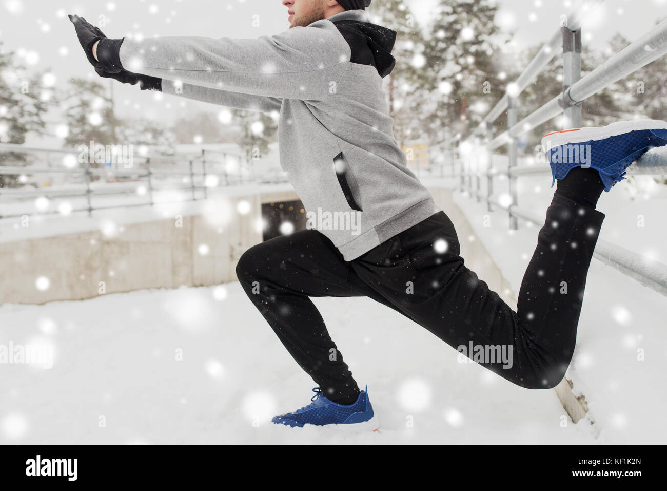 sports man stretching leg at fence in winter Stock Photo - Alamy
