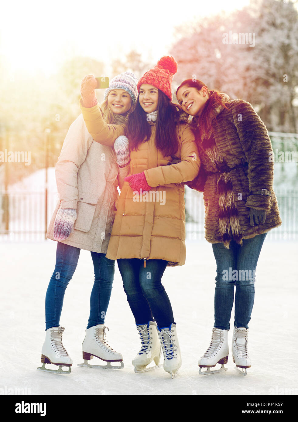 happy young women with smartphone on skating rink Stock Photo - Alamy