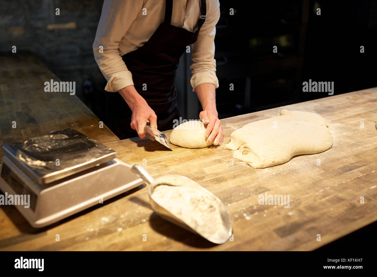 baker portioning dough with bench cutter at bakery Stock Photo - Alamy
