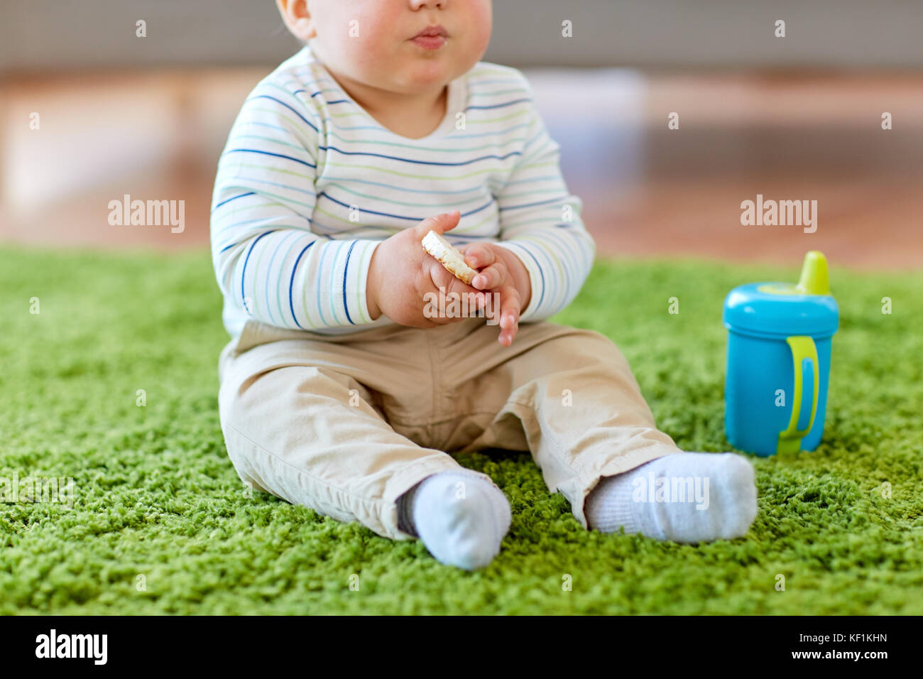 baby boy on floor and eating rice cracker at home Stock Photo - Alamy