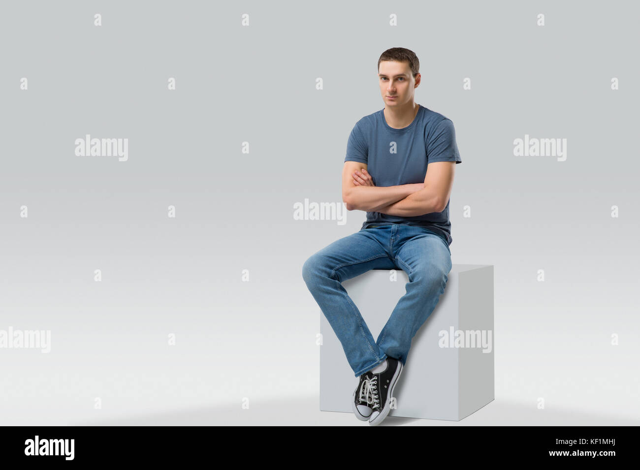 young man sitting on white cube. isolated. Space for text Stock Photo ...