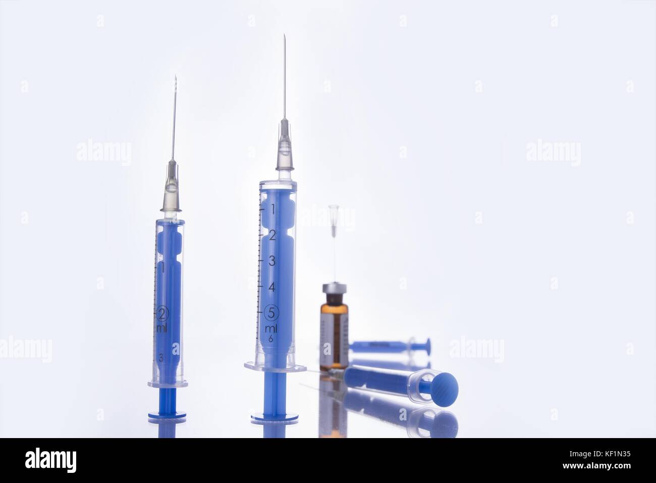 Two shots stand up and two injections laying on the white table Stock ...