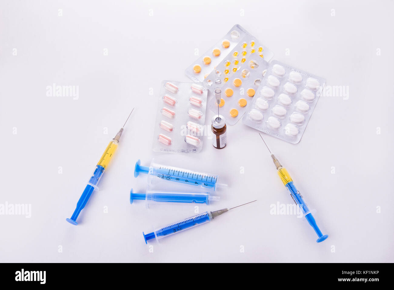 Filled up injections with needles and tablets on the white background ...