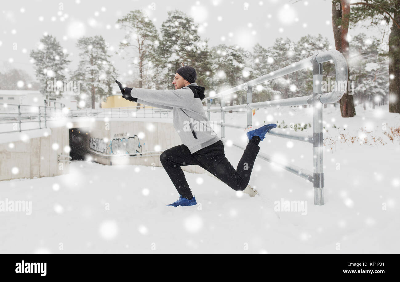 sports man stretching leg at fence in winter Stock Photo - Alamy