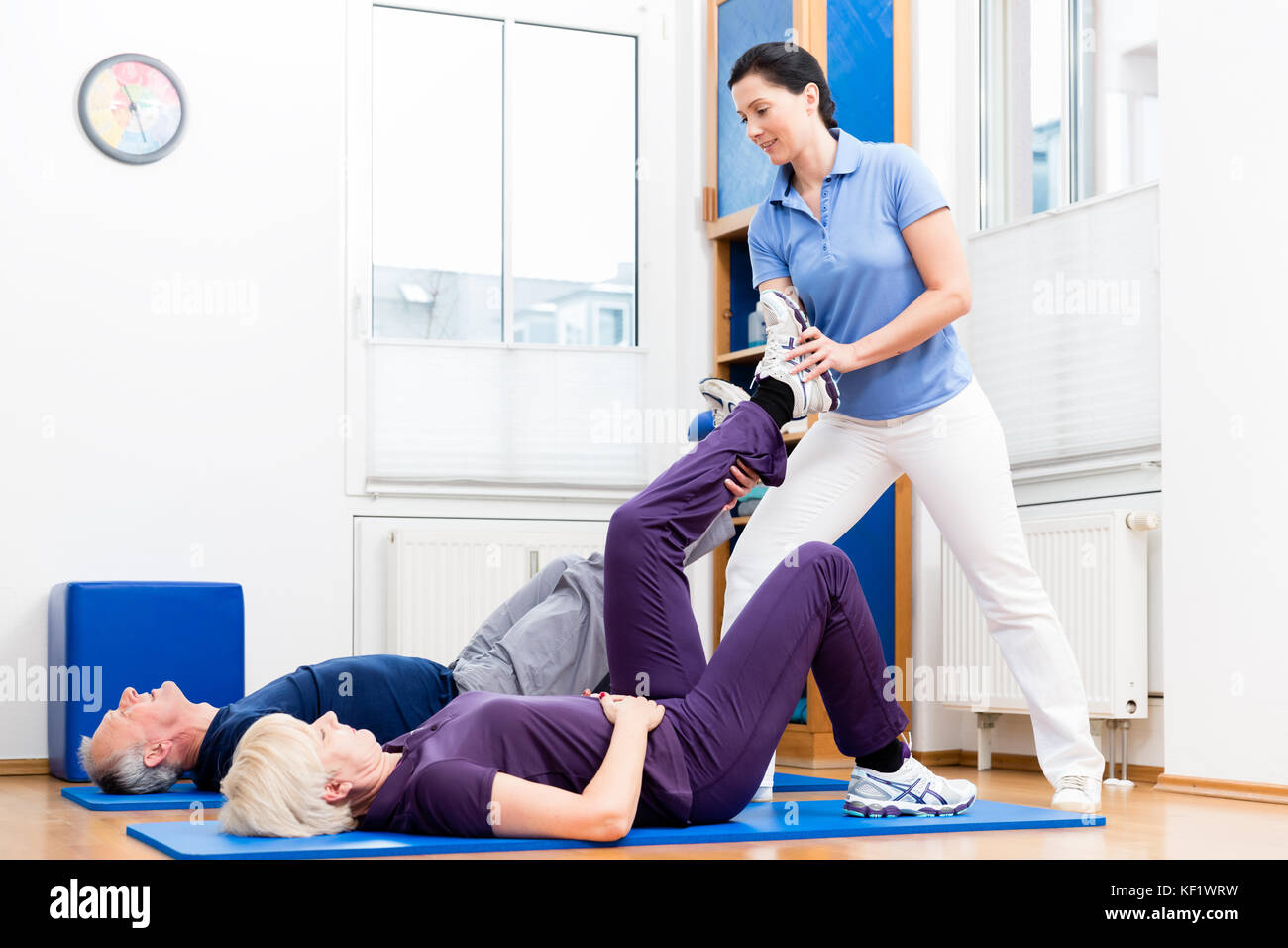 Senior woman and man doing assisted floor exercises with physiot Stock ...