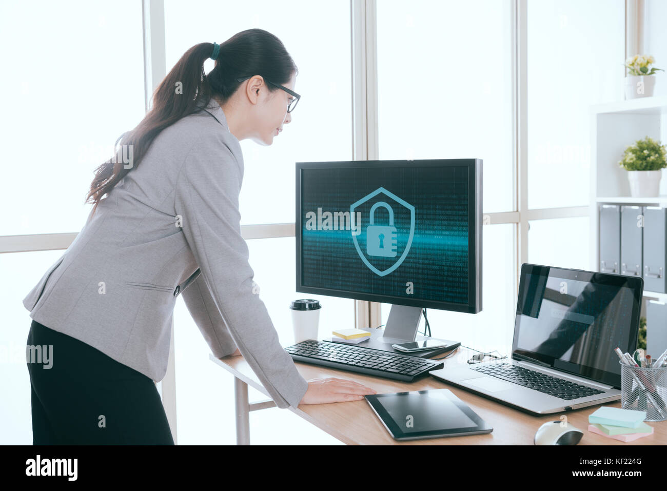 young professional business woman standing in front of working computer ...