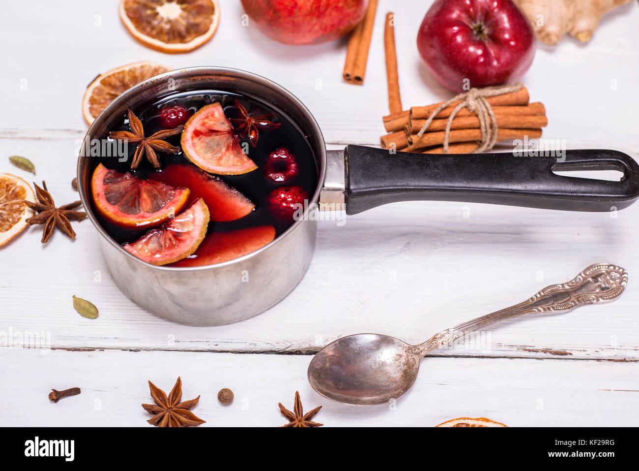 mulled wine in an aluminum ladle with a handle on a white wooden ...