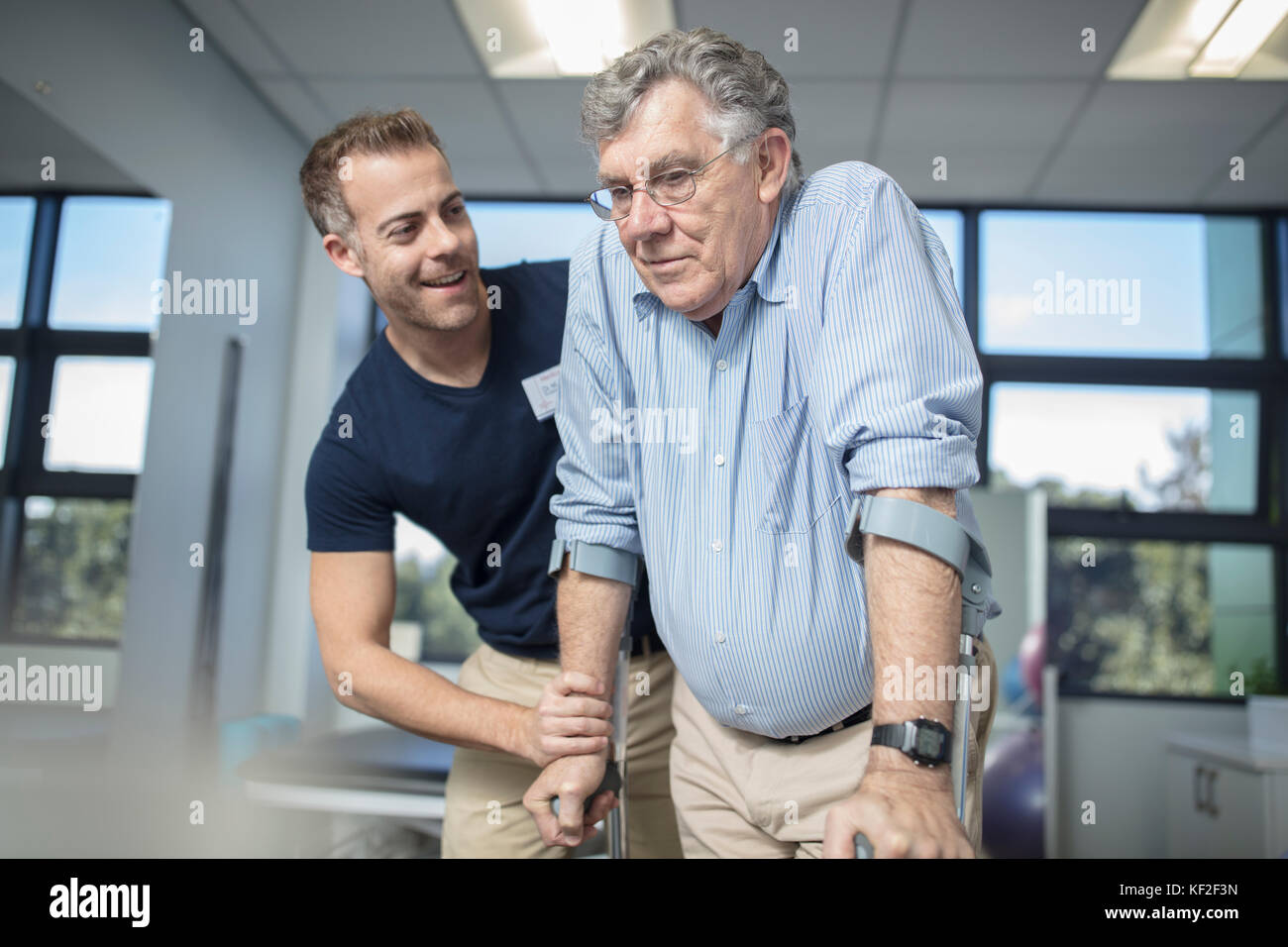 Physio helping senior patient with crutches Stock Photo - Alamy