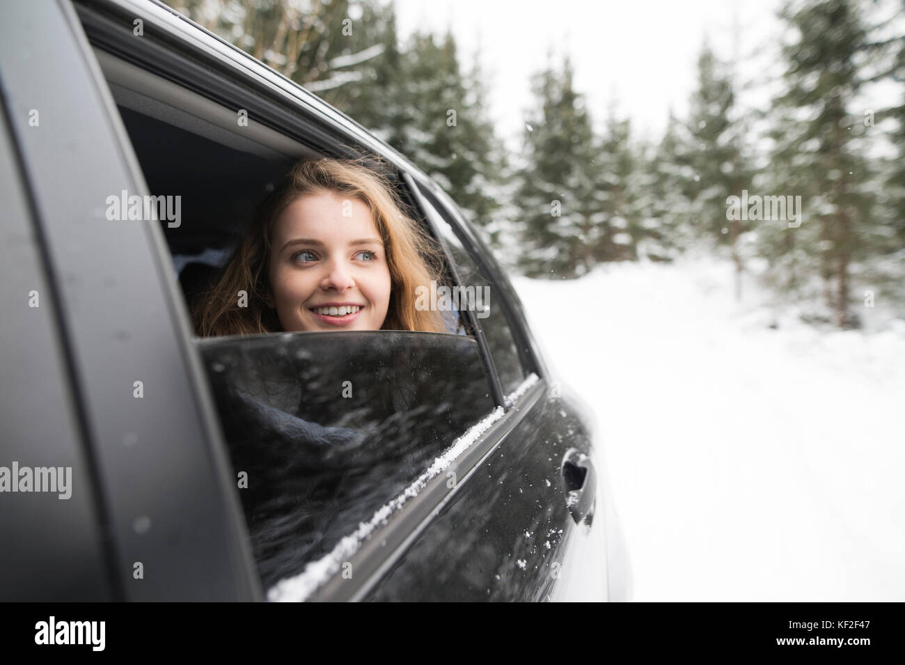 Young woman looking out of a car window in winter landscape Stock Photo ...