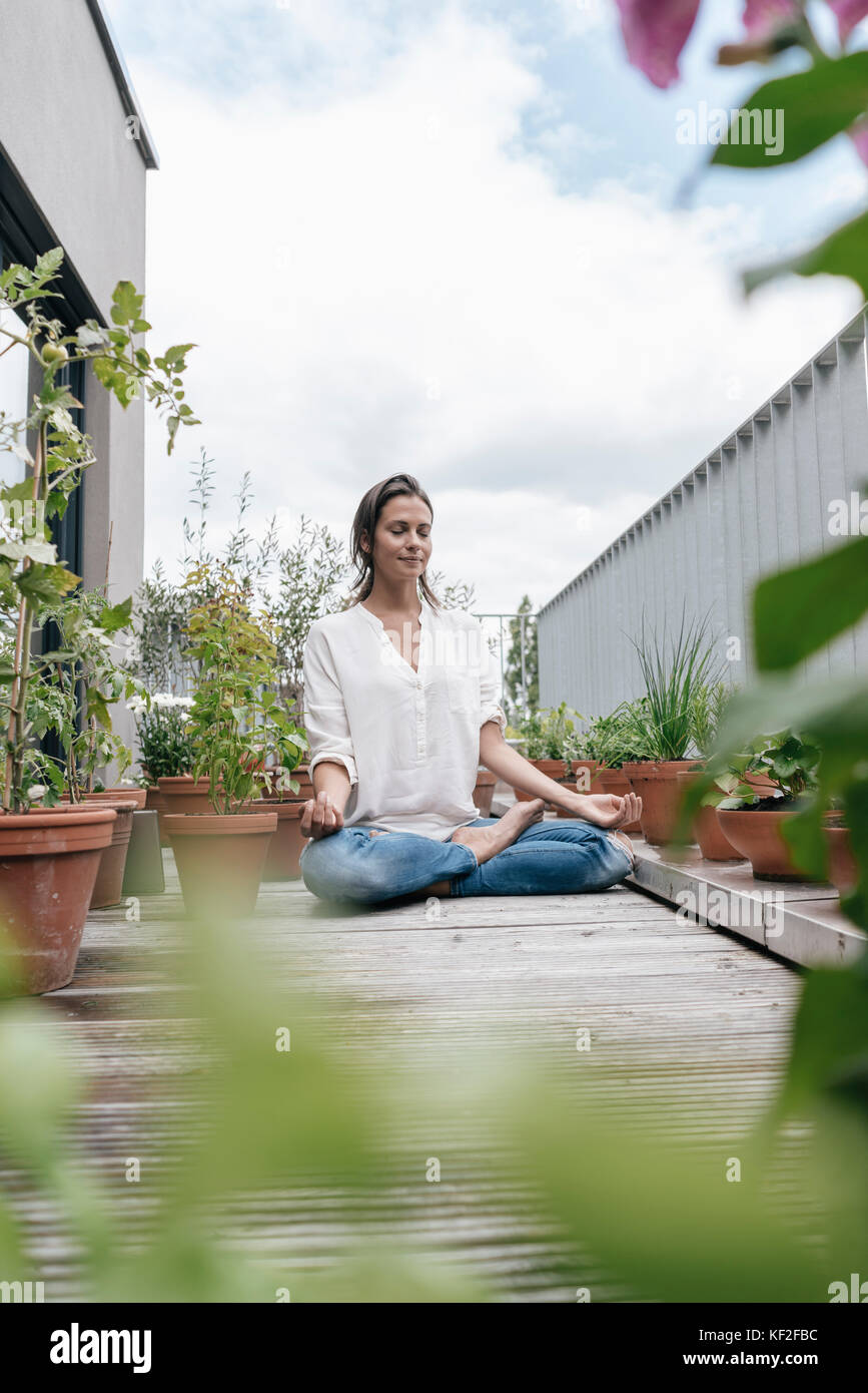 Woman sitting on balcony practicing yoga Stock Photo - Alamy