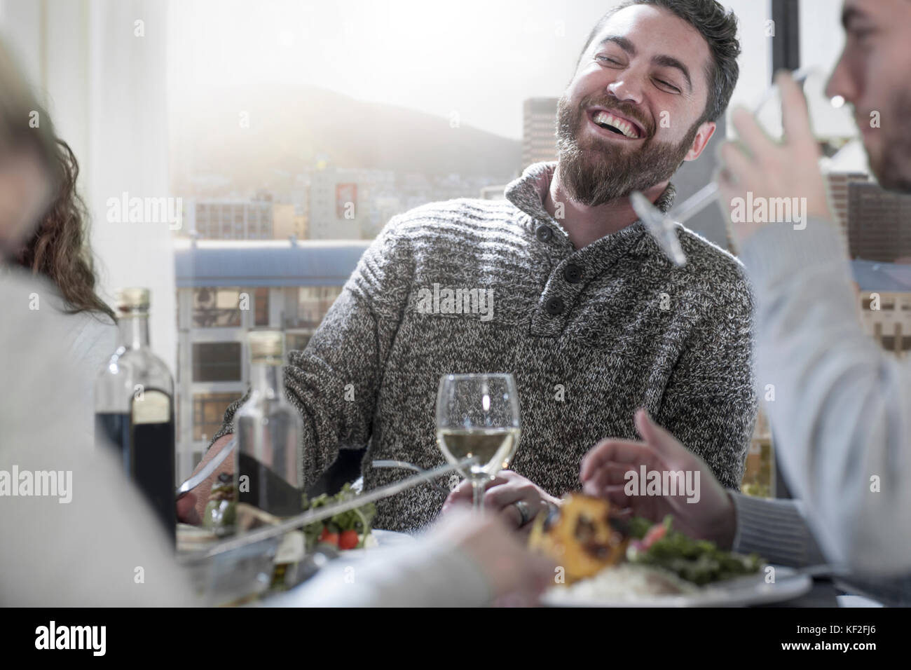 Man laughing at dinner table with friends Stock Photo - Alamy