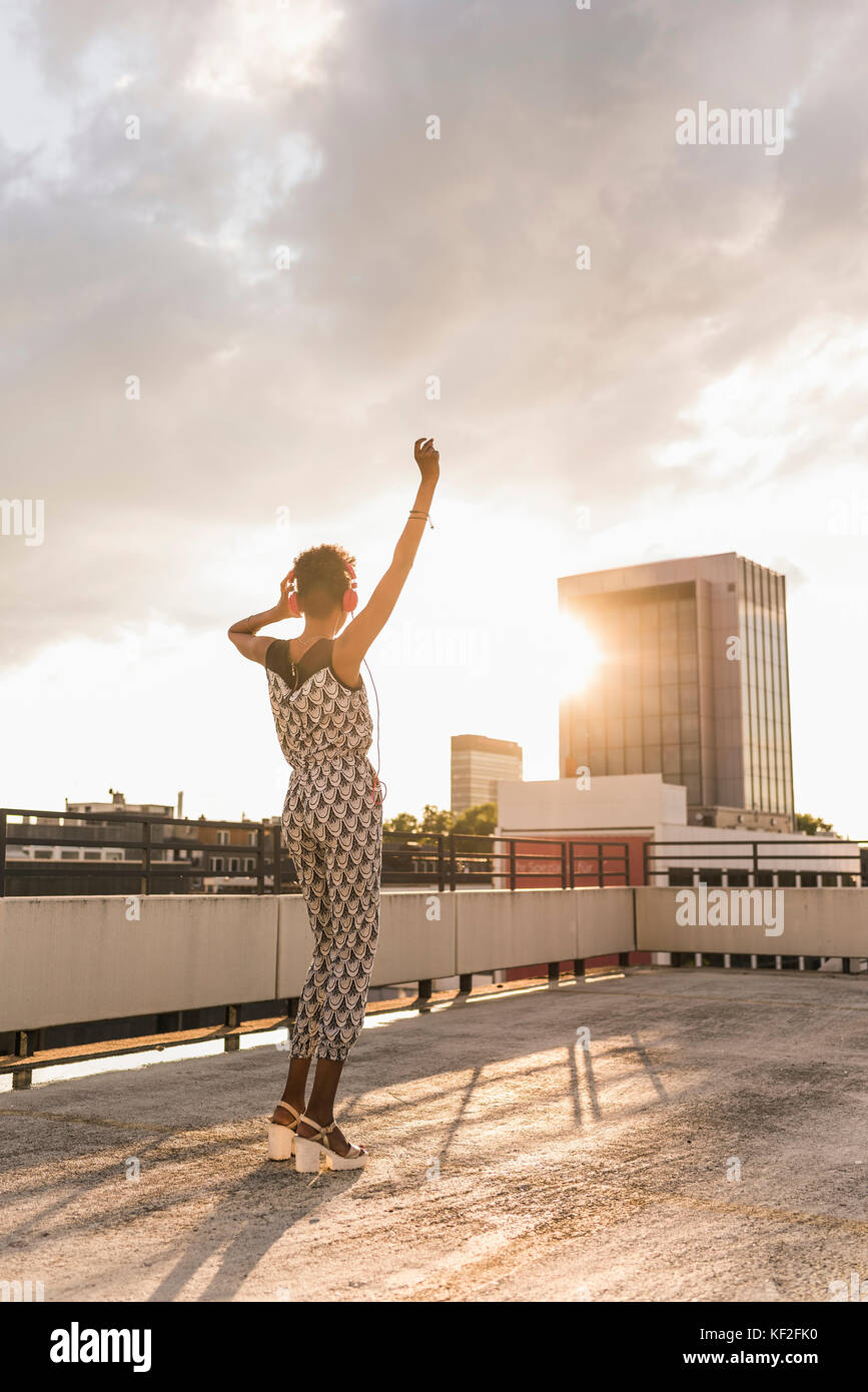Young woman with headphones dancing on rooftop Stock Photo - Alamy