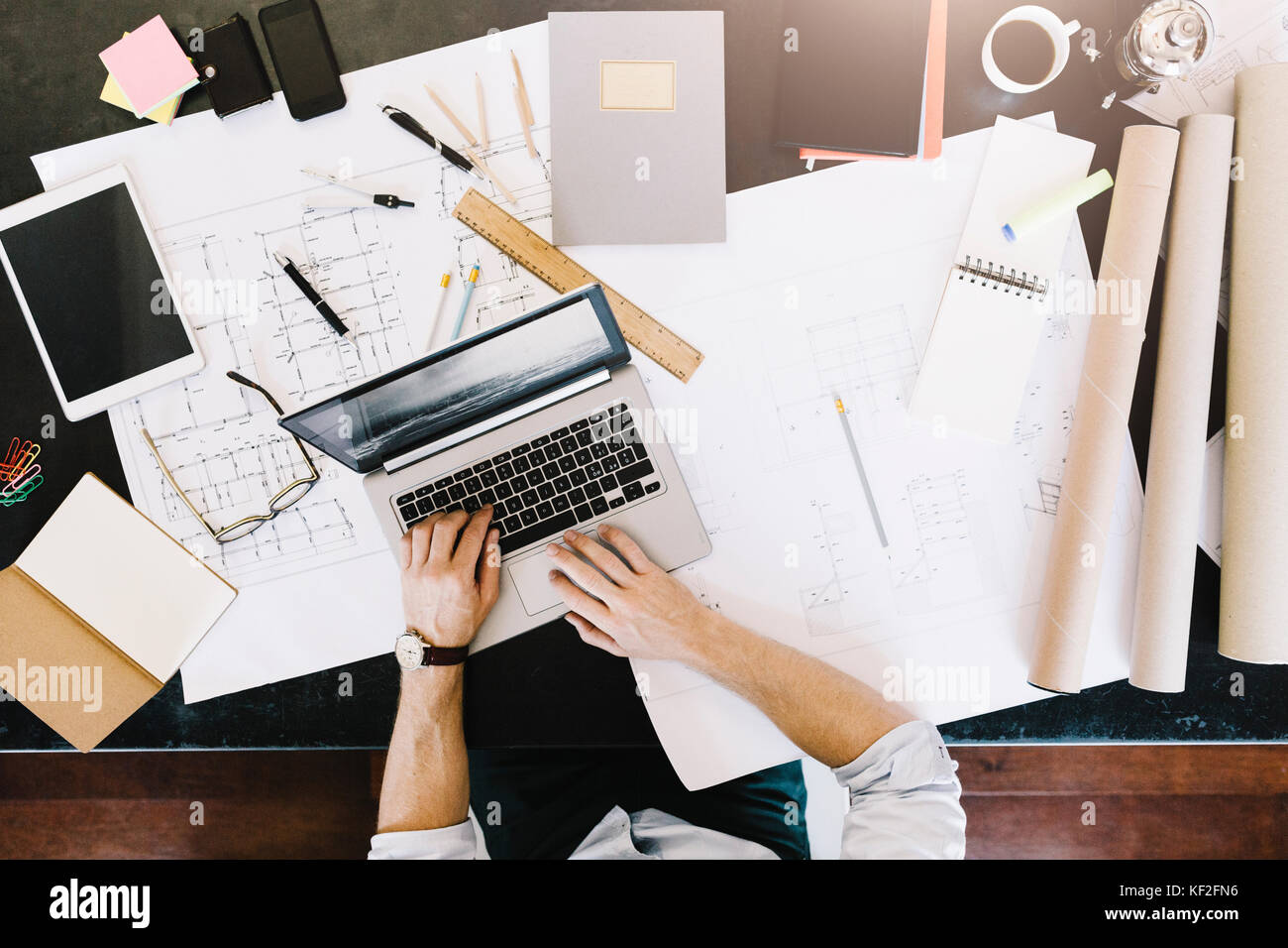 Man using laptop next to construction plan at desk, top view Stock ...