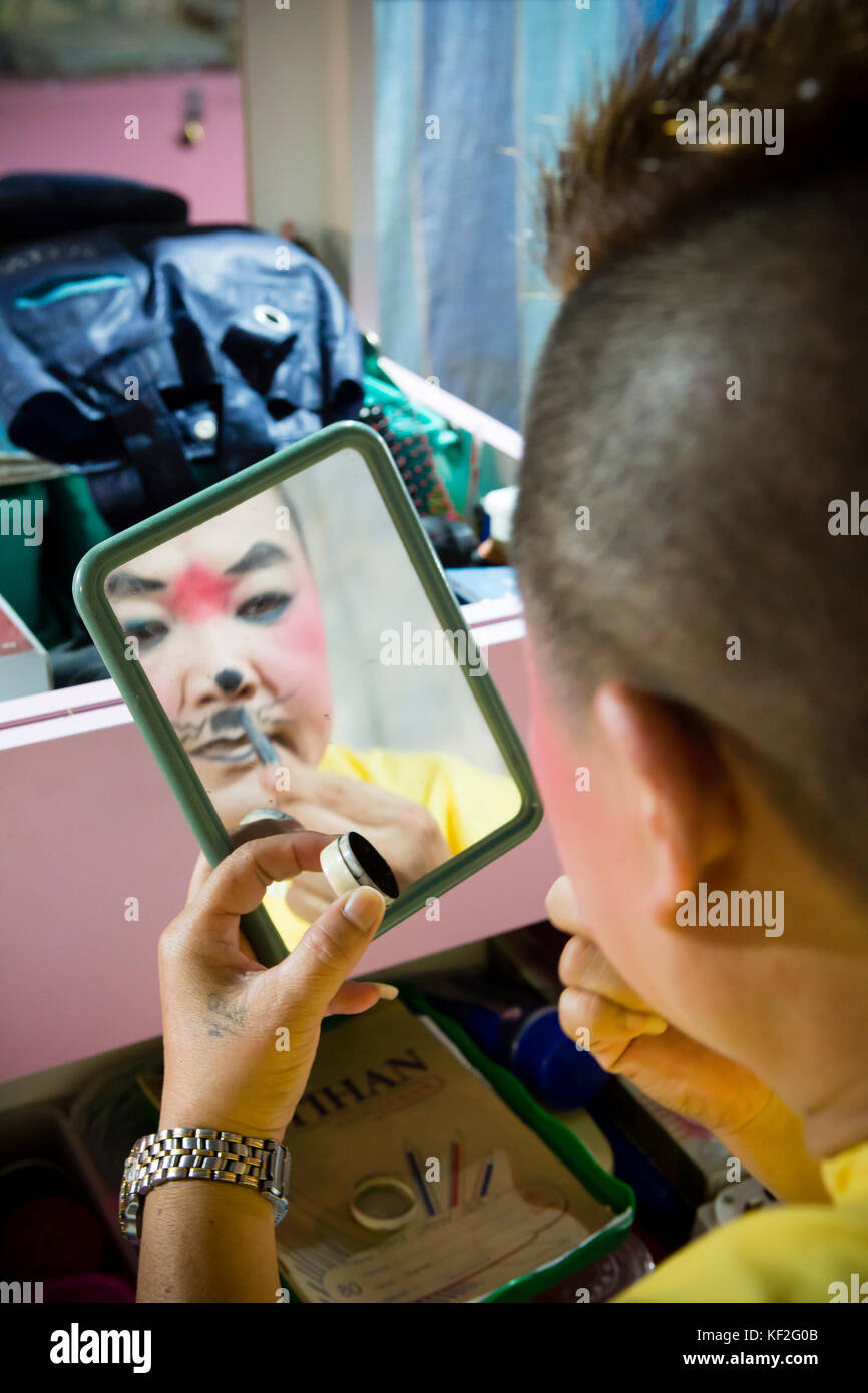 A female traditional Chinese opera performer applying makeup backstage ...