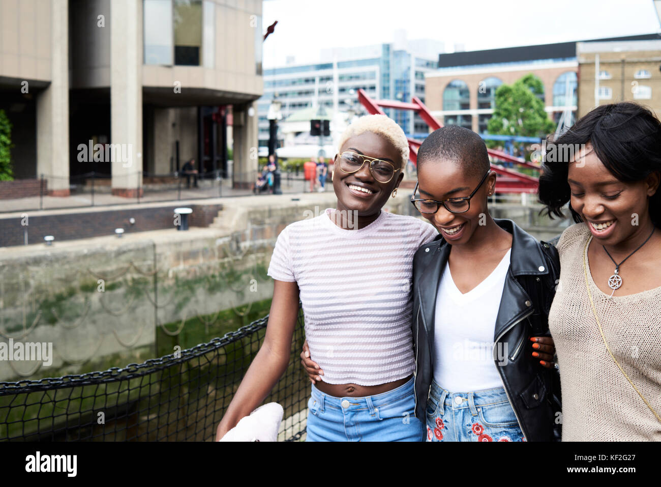 Three happy friends walking arm in arm Stock Photo - Alamy