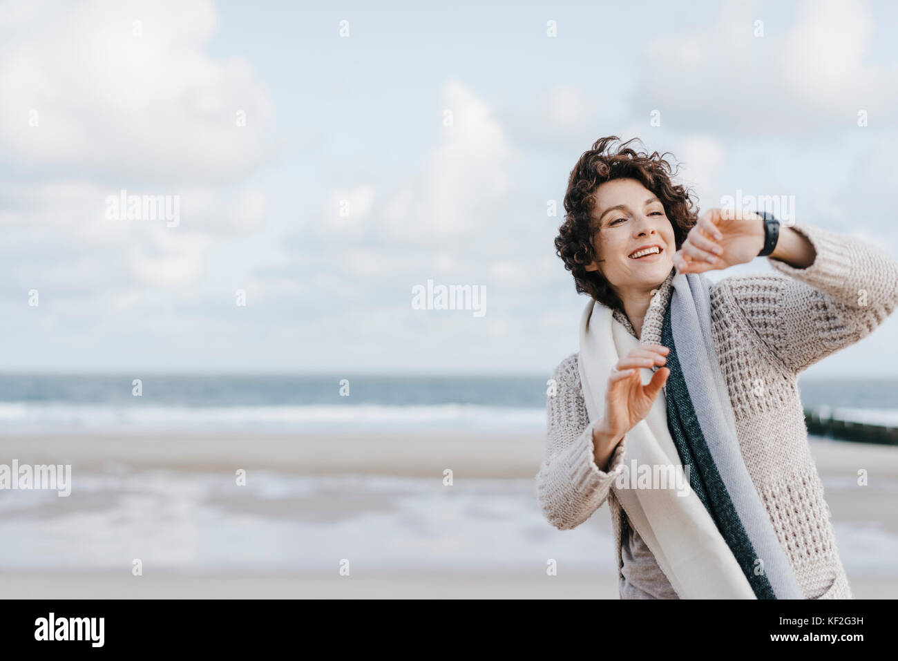 Woman on the beach looking at her smartwatch Stock Photo - Alamy