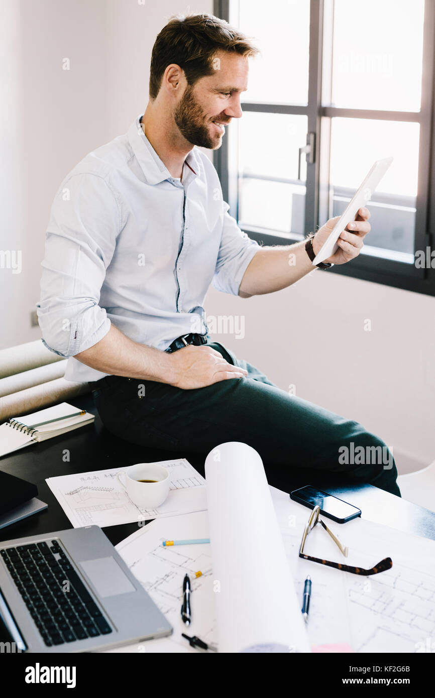 Architect sitting on desk in his office using tablet Stock Photo - Alamy