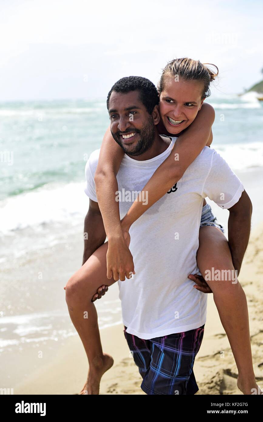 Man giving girlfriend piggyback ride on the beach Stock Photo - Alamy