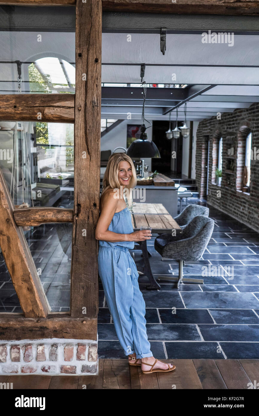 Woman standing in her comfortable country house, smiling Stock Photo ...