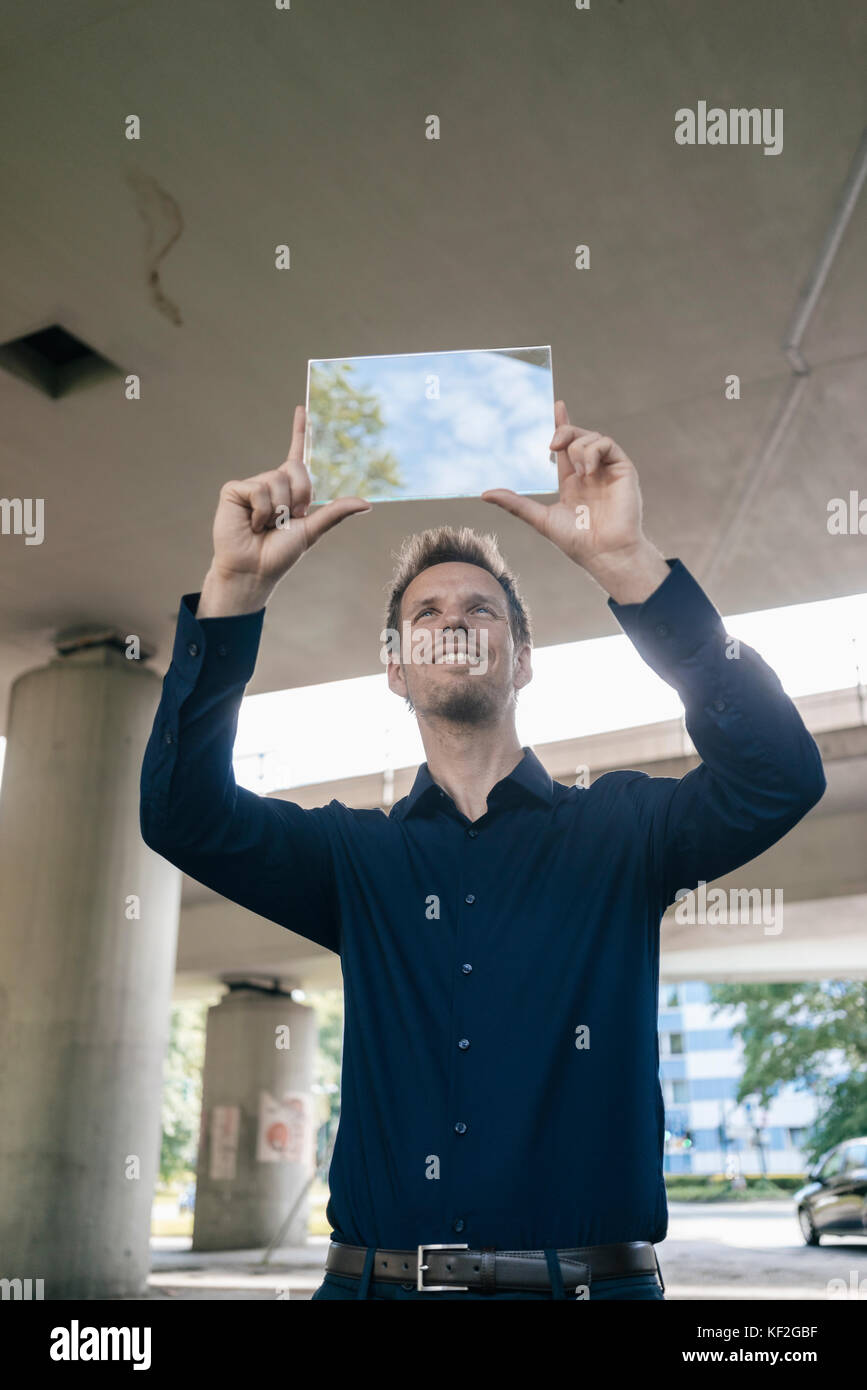 Smiling businessman holding up portable glass device Stock Photo - Alamy