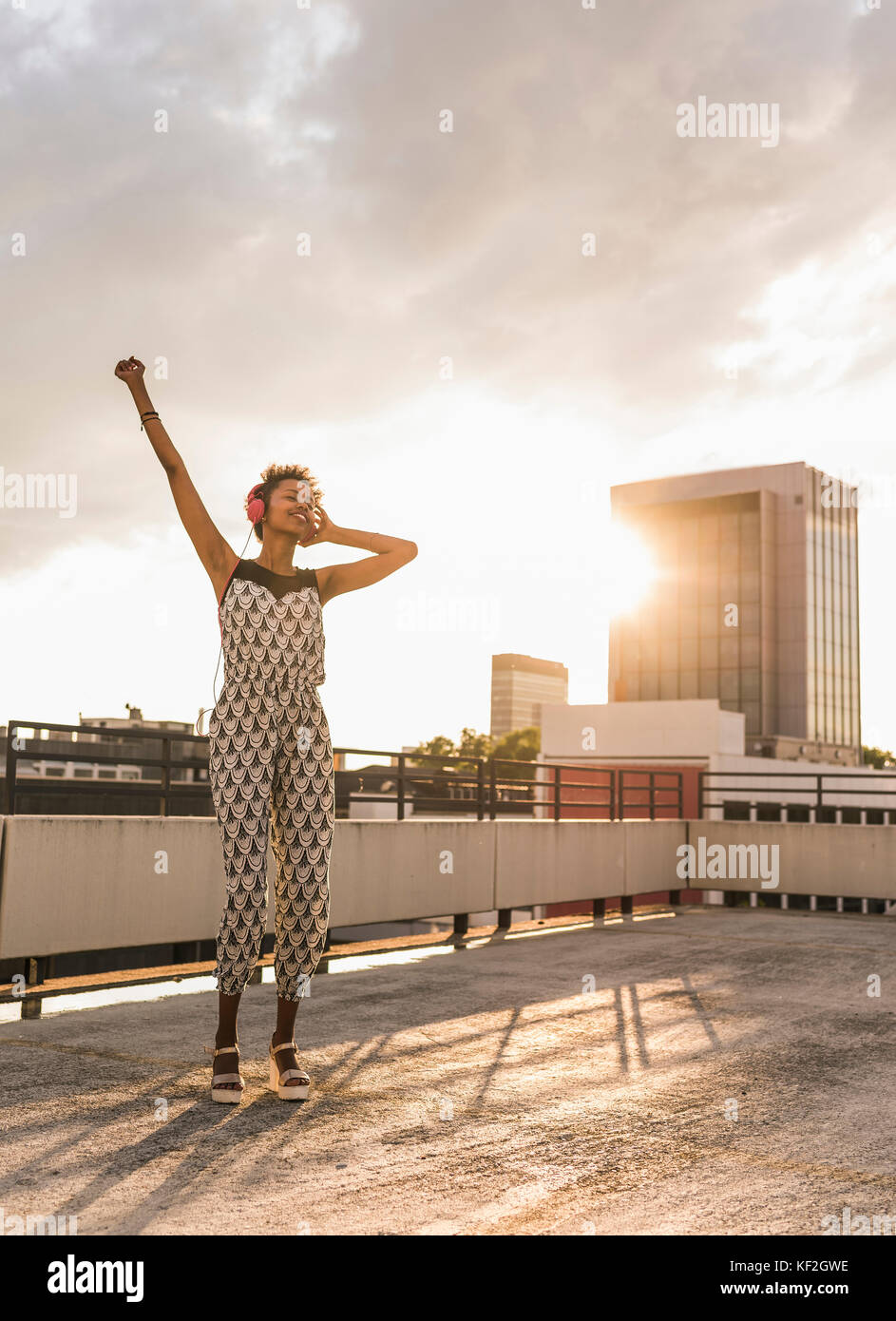 Young woman with headphones dancing on rooftop Stock Photo - Alamy