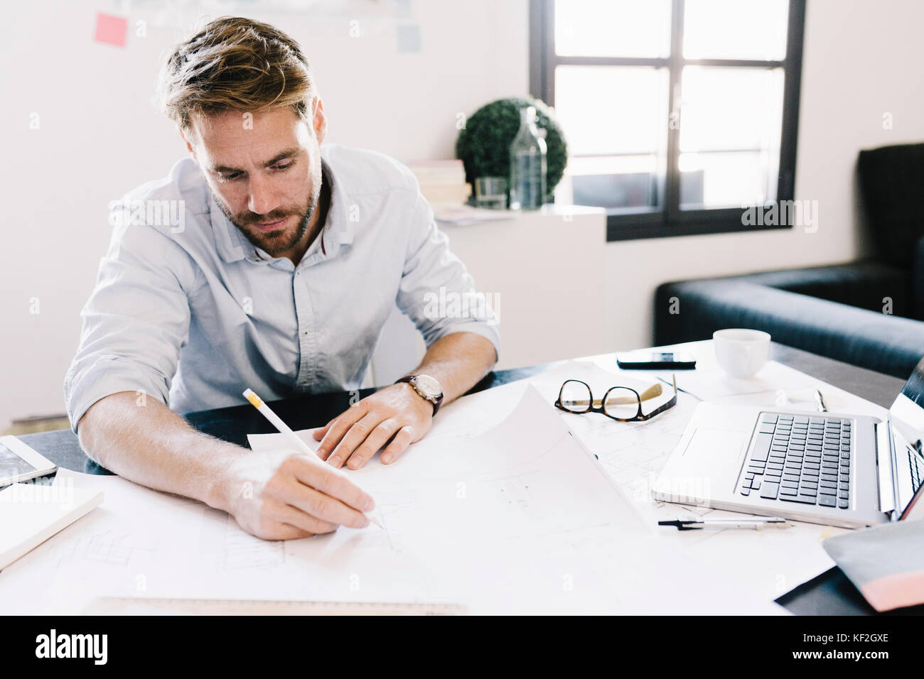 Architect working on construction plan at desk Stock Photo - Alamy