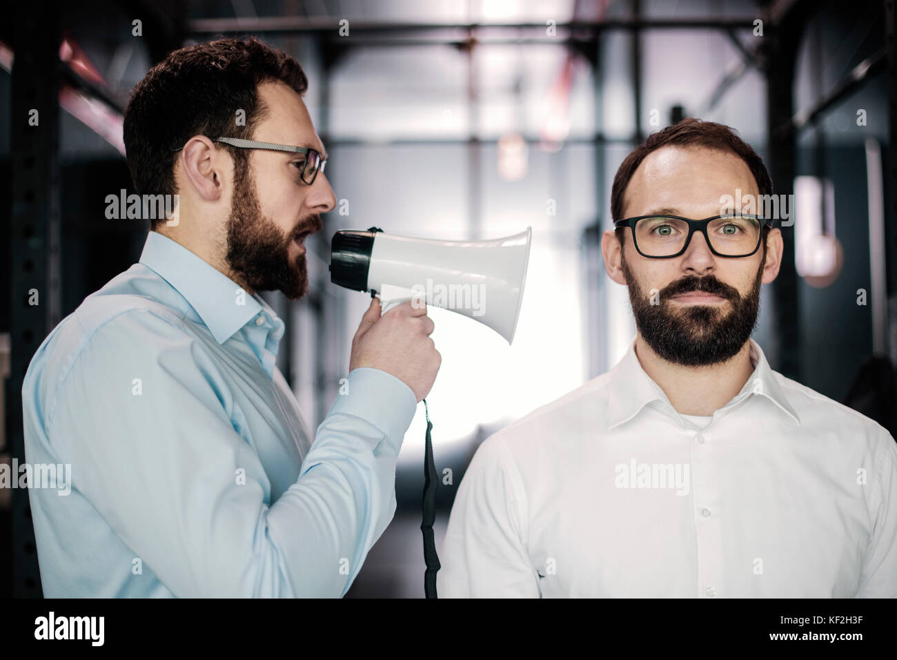Manager with megaphone giving businessman orders Stock Photo - Alamy