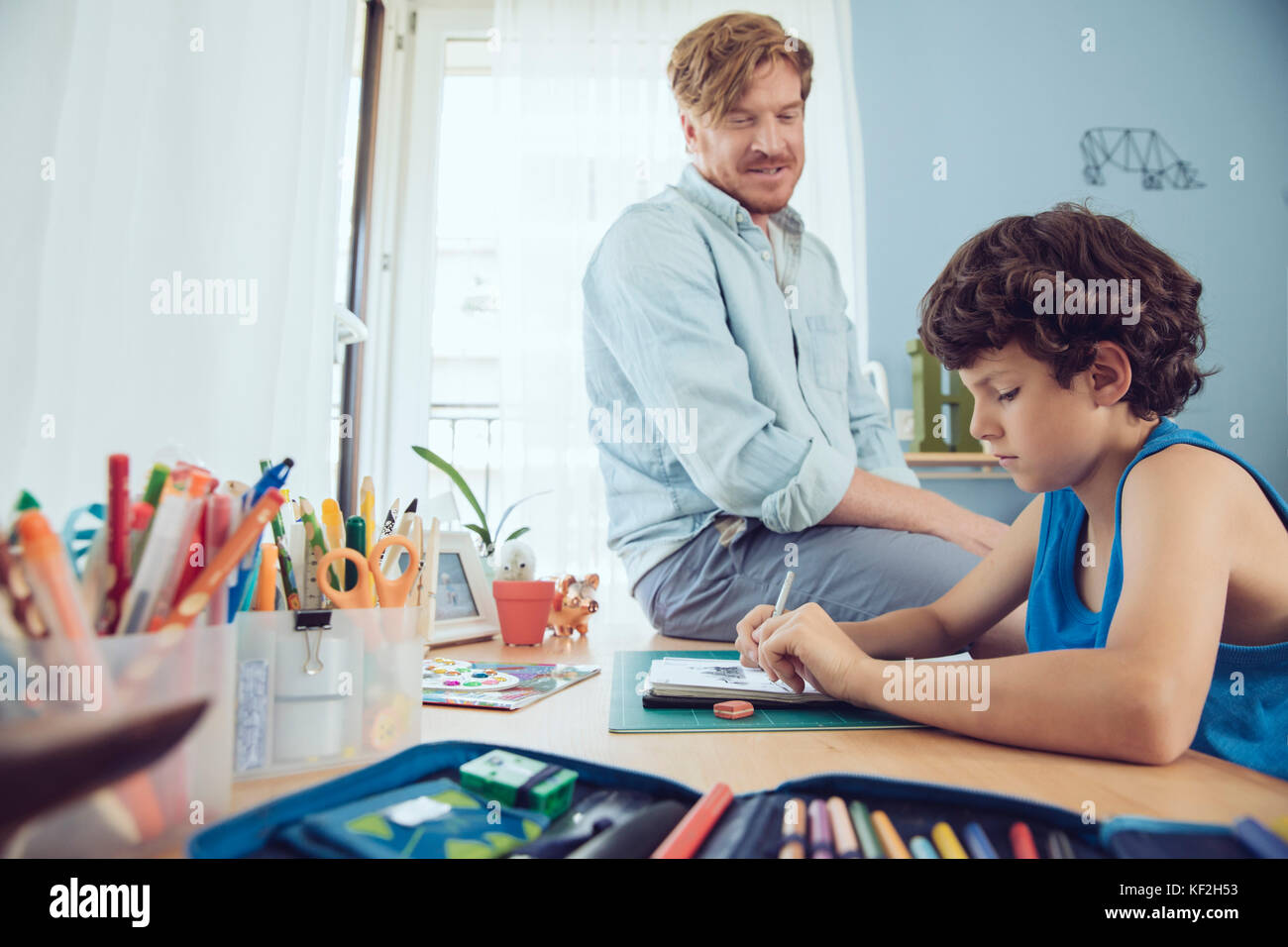 Father helping boy doing his schoolwork at home Stock Photo - Alamy