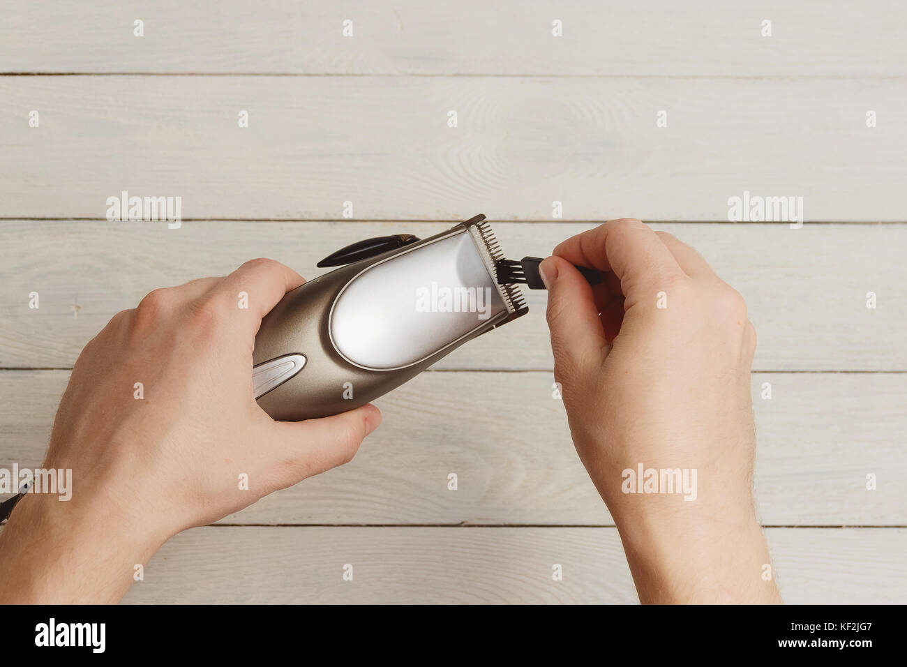 Man Hand holding hair clippers on white wooden background Stock Photo ...