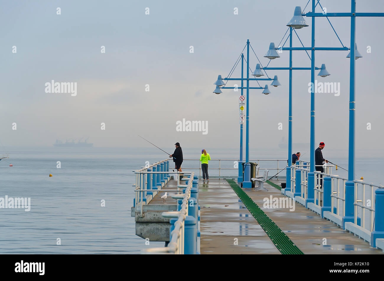 People fishing off modern jetty on foggy morning, Palm Beach jetty ...